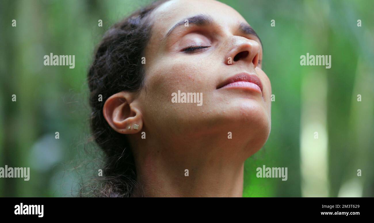 Woman with eyes closed taking a deep breath in meditation in nature ...