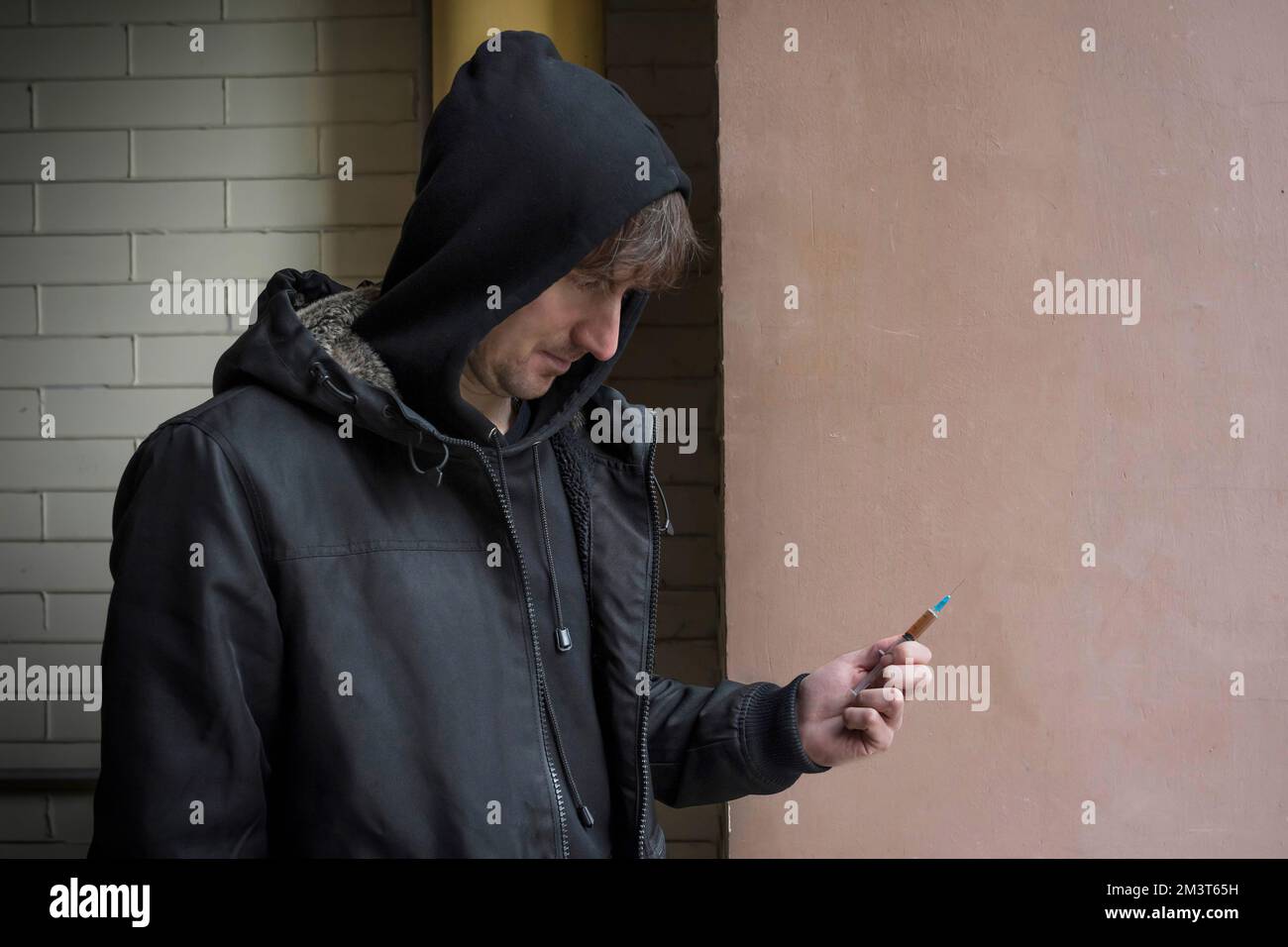 Addict with a syringe in his hand on the street. Addiction concept ...