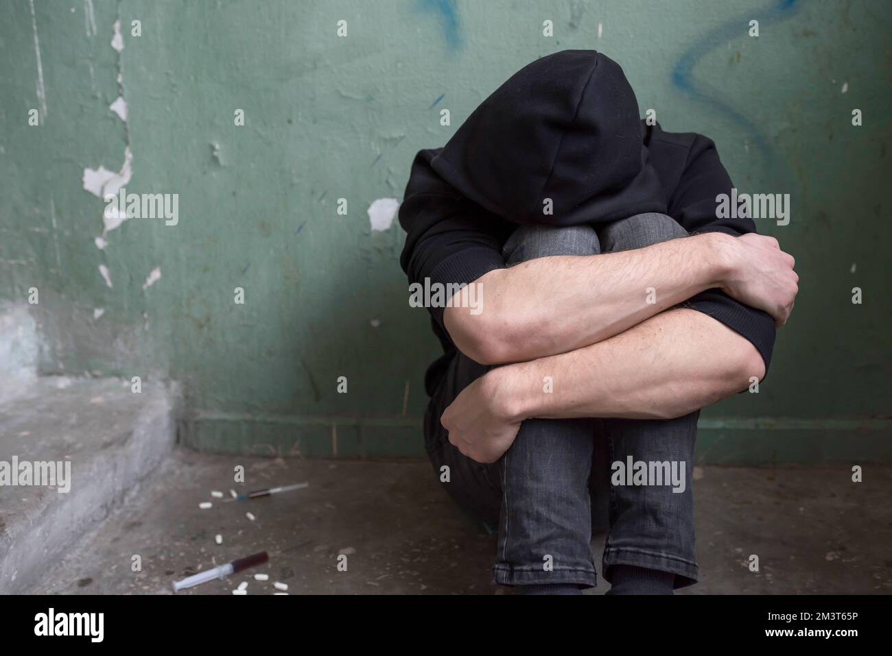 A teenage drug addict sits alone after using drugs and alcohol in an ...