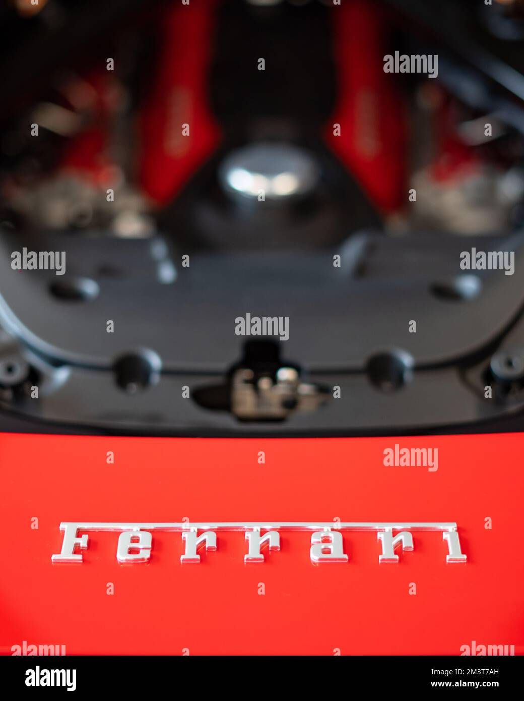 A vertical shot of a rear end of a red Ferrari with an open engine ...