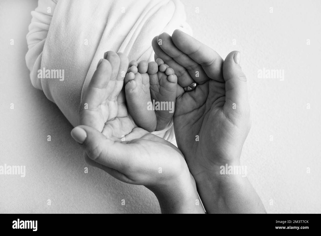 The palms of the father, the mother are holding the foot of the newborn ...