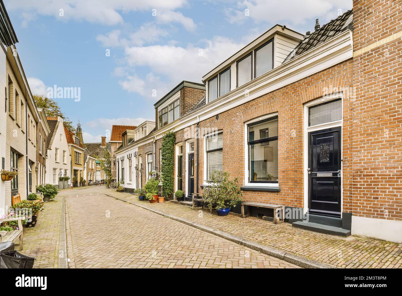 an old street in the netherlands with brick buildings and plants on ...