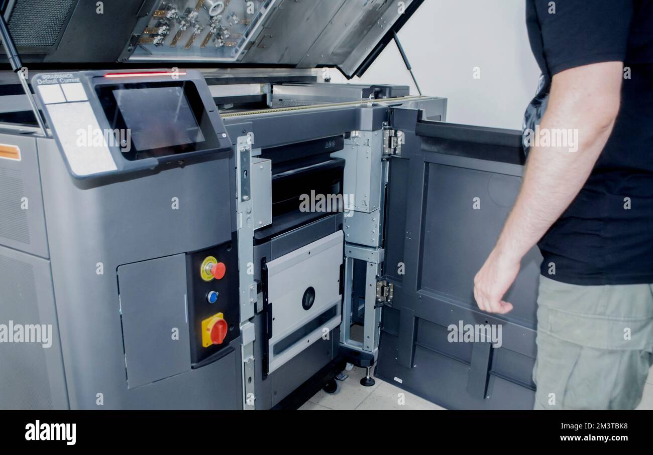 A man worker and a large industrial powder 3d printer in a laboratory ...