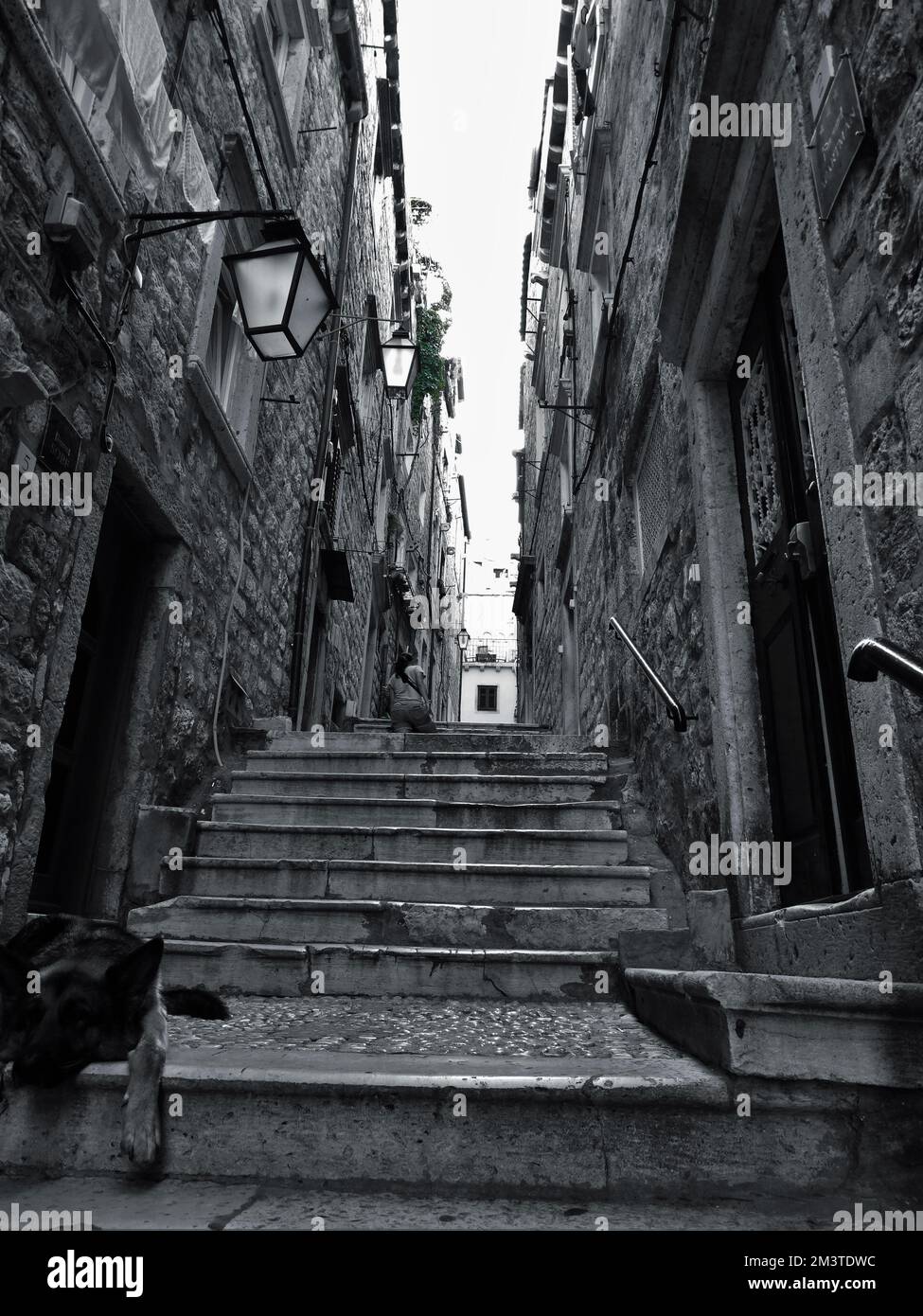 A grayscale shot of a narrow street with stairs Stock Photo - Alamy