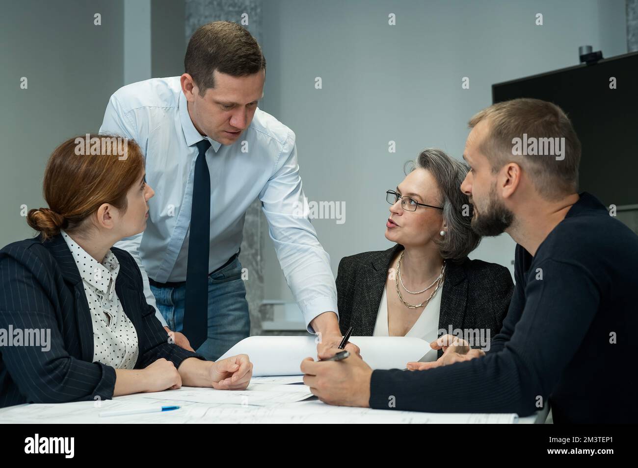 The boss gives instructions to three employees in the office conference ...