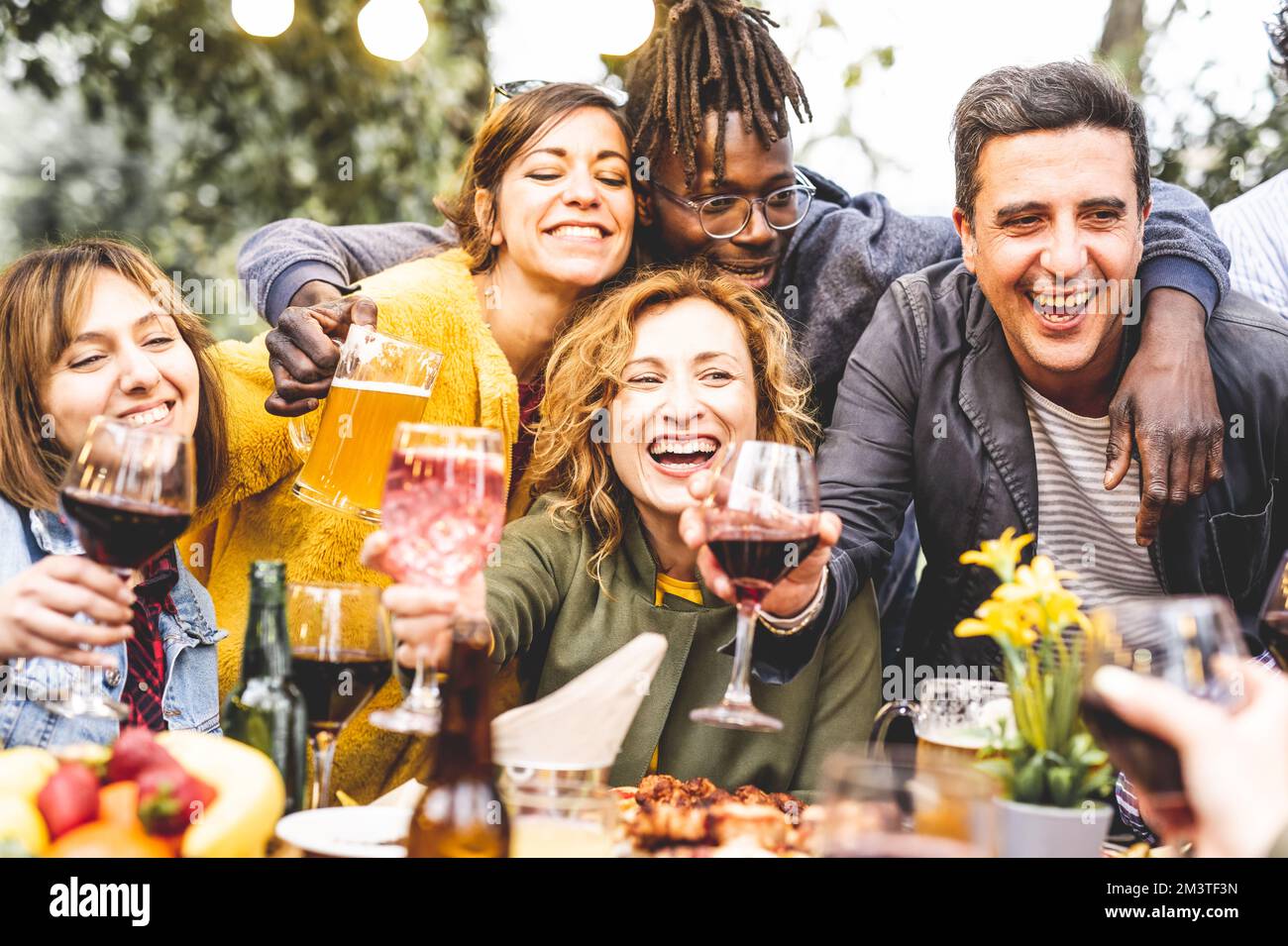 Group pf smiling friends drinking and toasting at private party ...