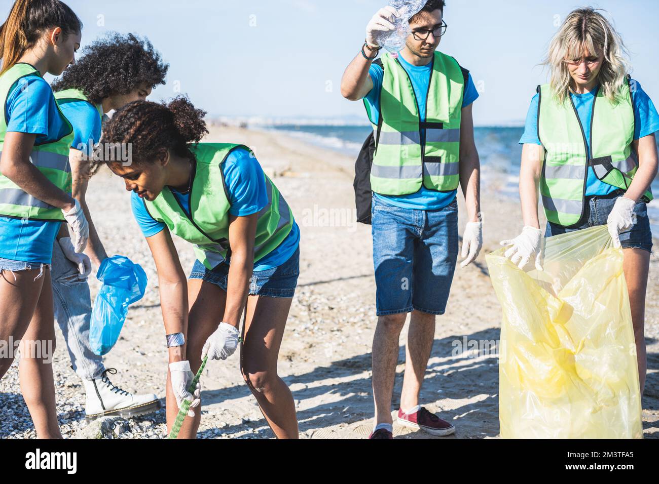 Volunteers collecting garbage on the coast line, young people working ...