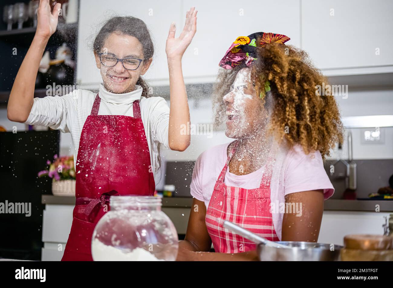 Mom and daughter play with flour while preparing sweets at home ...