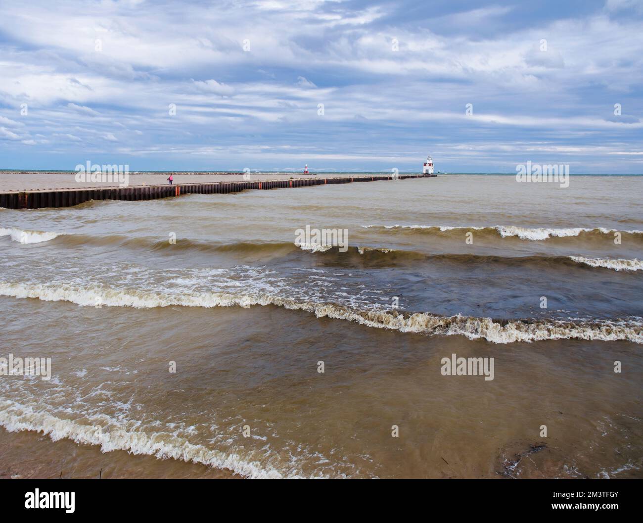 Waves come onshore while at the end of a long pier sits the Kewaunee ...