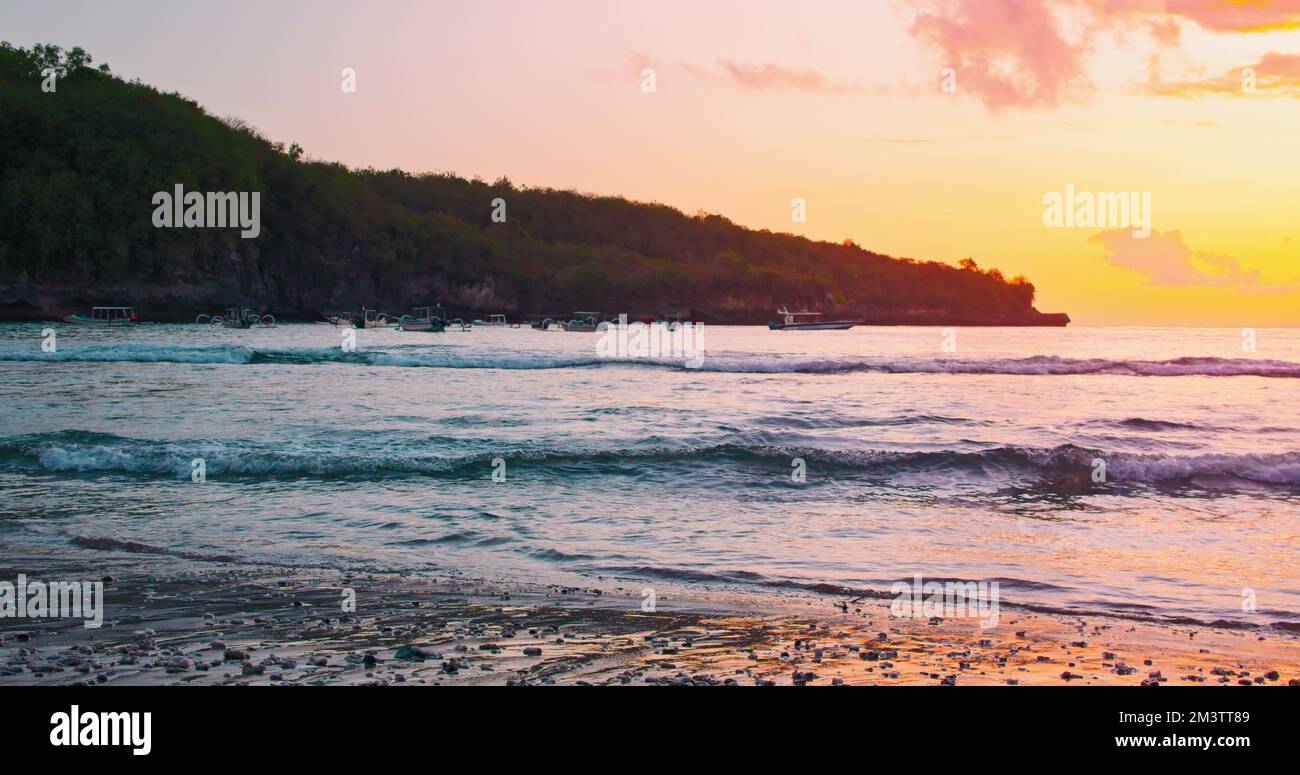 Close-up of waves spreading out over a beach at colorful sunset. Sea ...