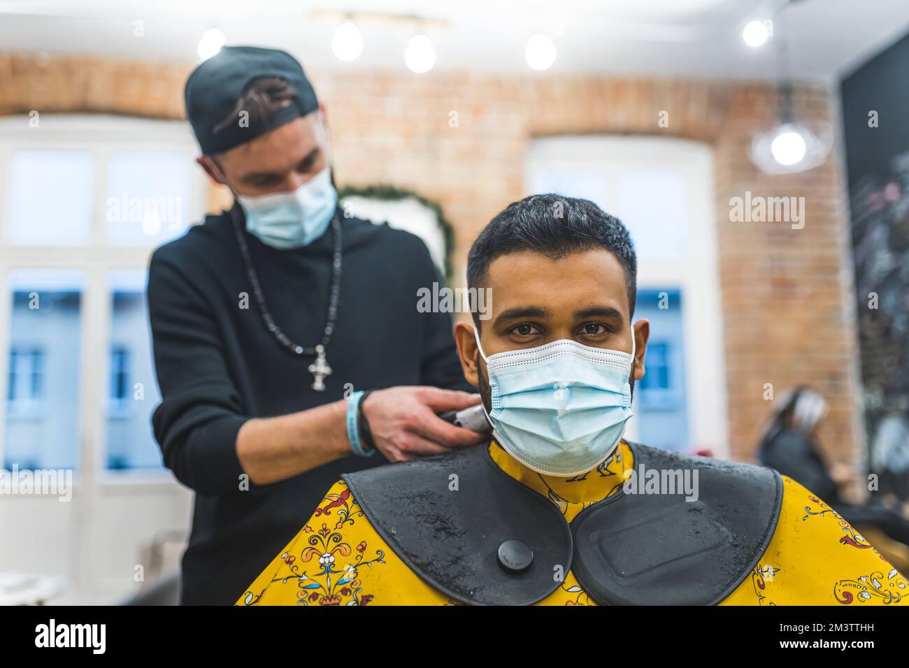 Professional barber wearing a mask trimming indian client's hair ...