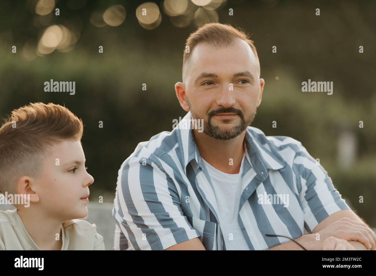 Father and son are sitting on the steps in the garden of an old ...
