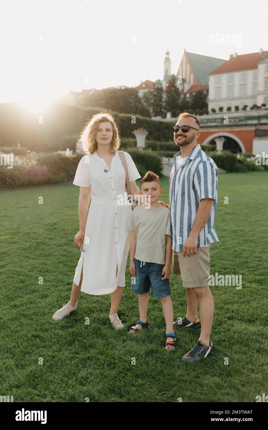 Father, mother, and son are hugging in the garden of an old European ...