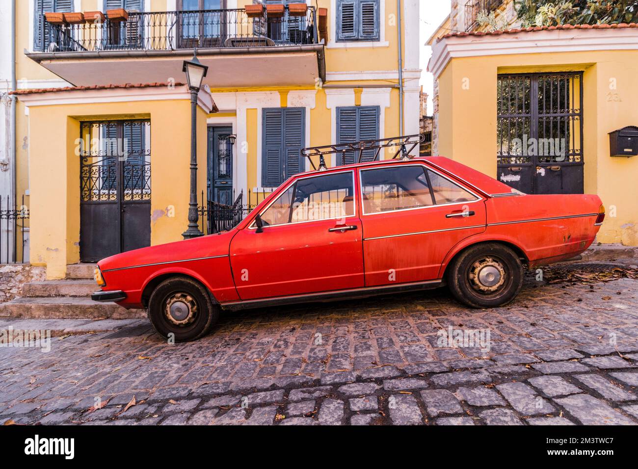 A vintage, red car standing in front of the urban house with yellow ...