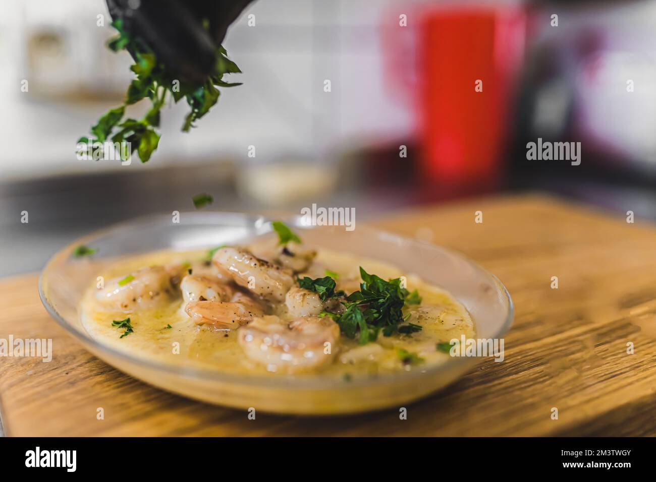 Prawns in spicy sauce with parsley. Chef preparing restaurant food. Blurred background. Eating ...