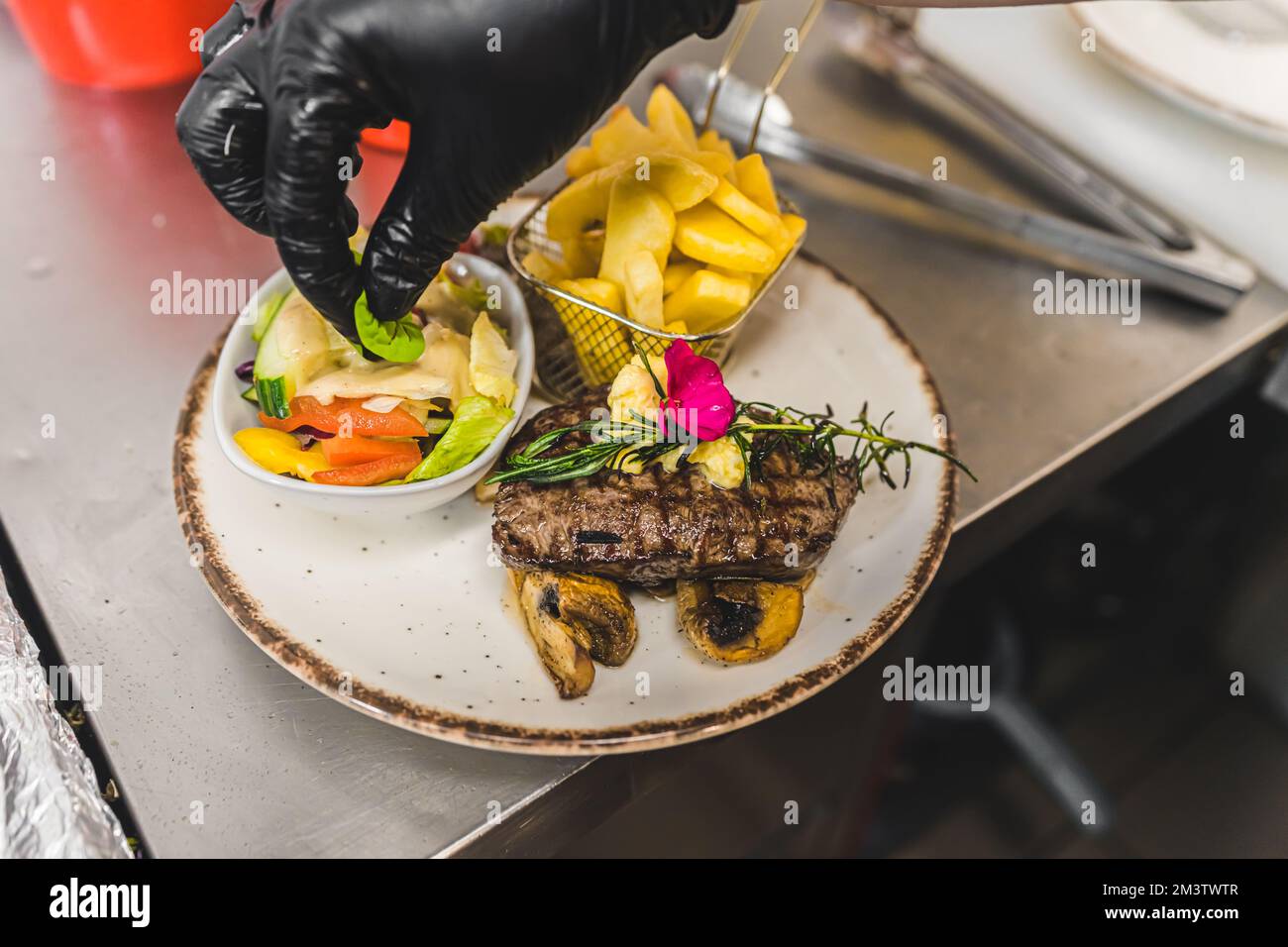 Restaurant dish decorating process. Professional chef in a black rubber ...