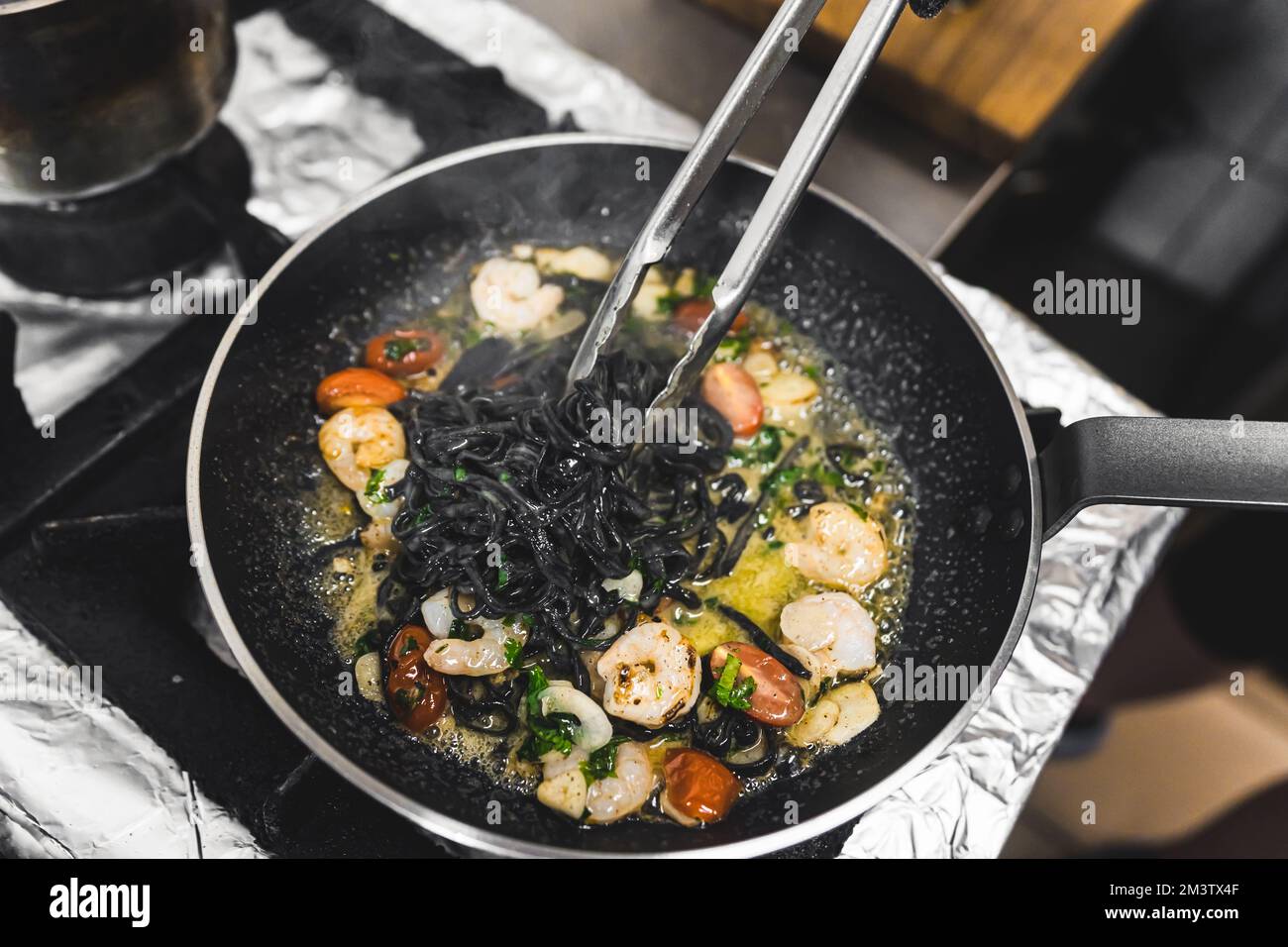 Black tagliolini pasta added to fried shrimps and cherry tomatoes ...