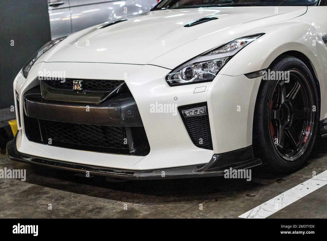 A closeup shot of the front of a white Nissan GT-R sportscar in a ...