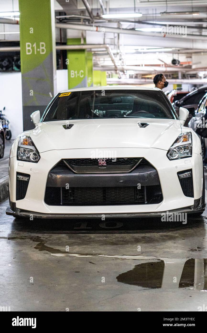 A vertical shot of a white Nissan GT-R sportscar in a parking lot Stock ...