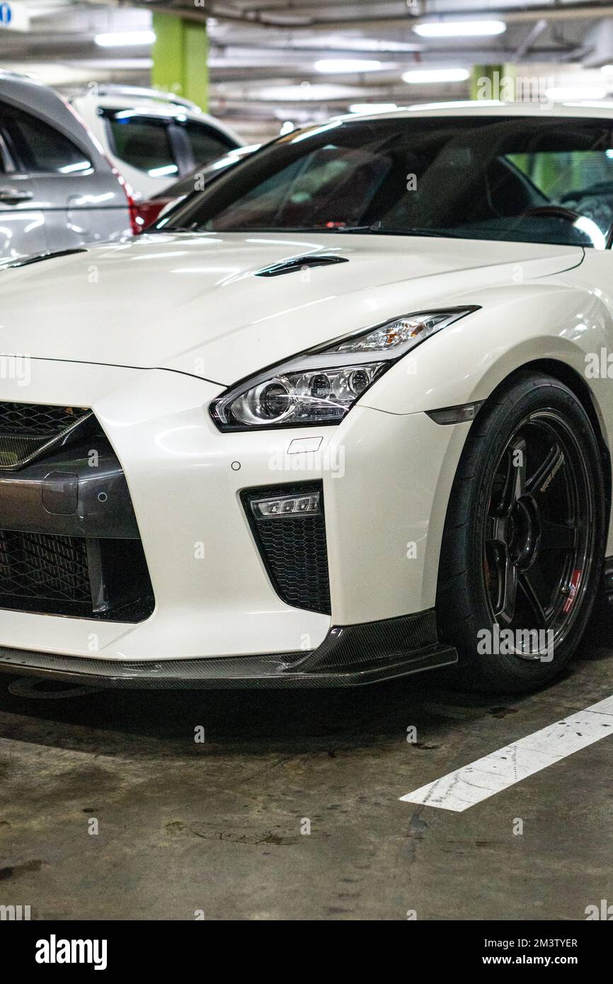 A vertical shot of a white Nissan GT-R sportscar in a parking lot Stock ...