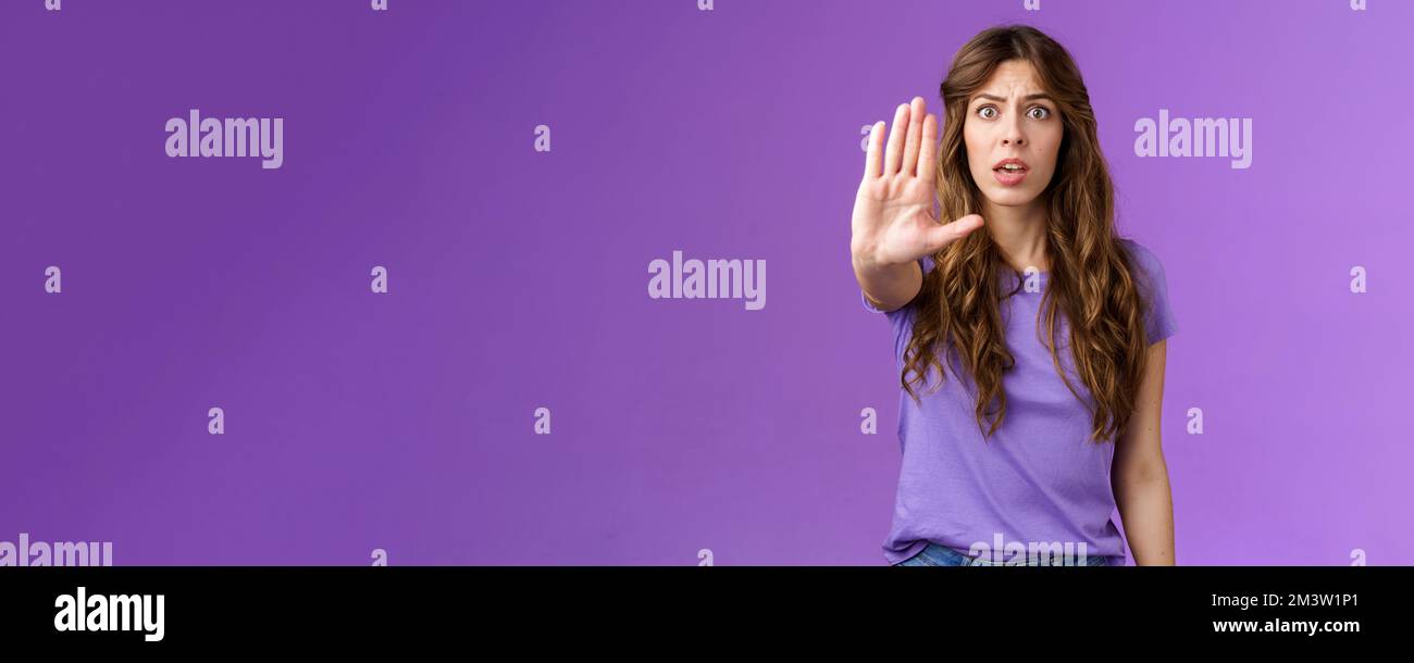 Worried shocked curly-haired woman gasping stare camera anxiously pull ...