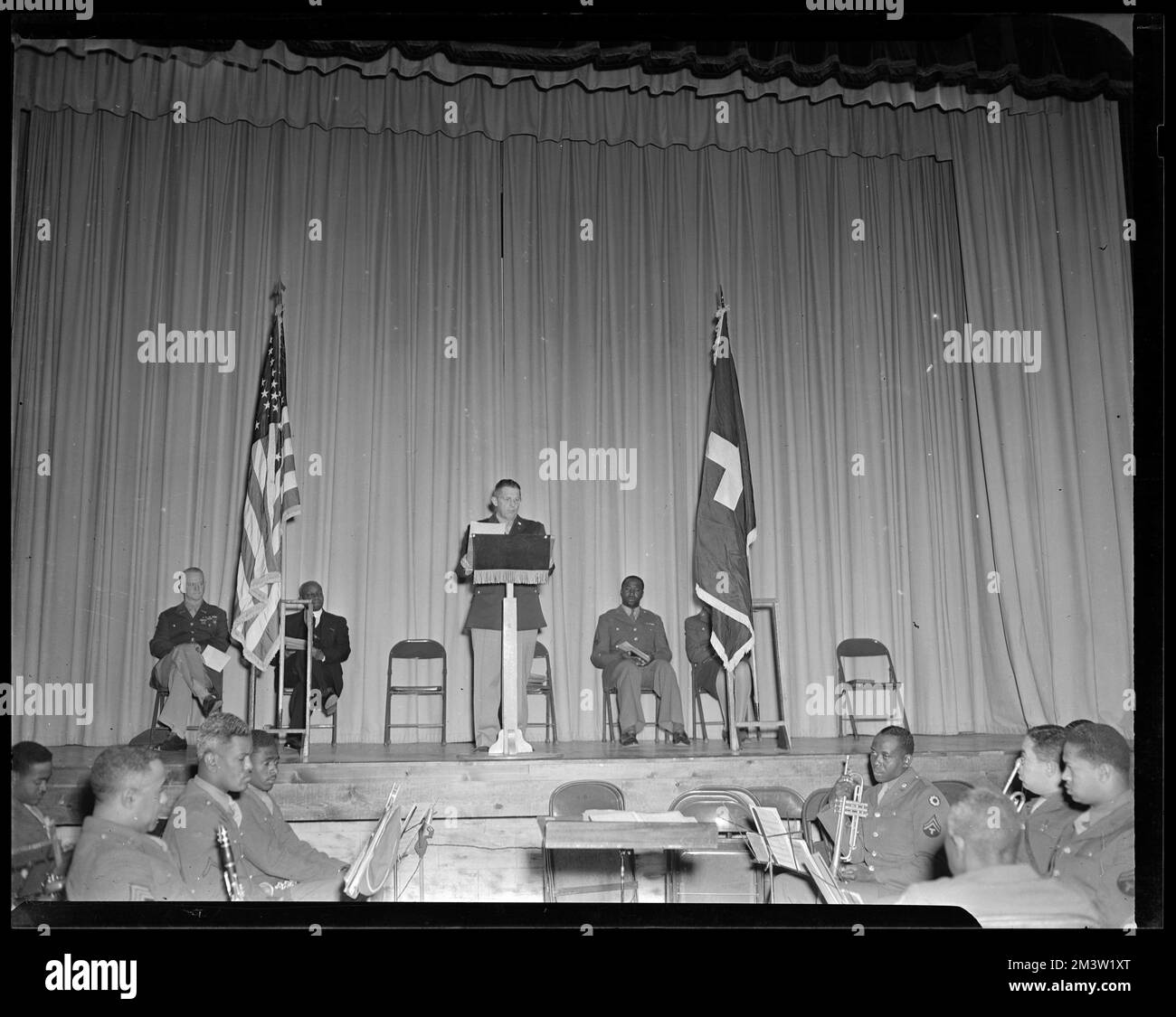 Speaker at lectern on stage , Soldiers, Flags, Musicians. Jack Miller ...