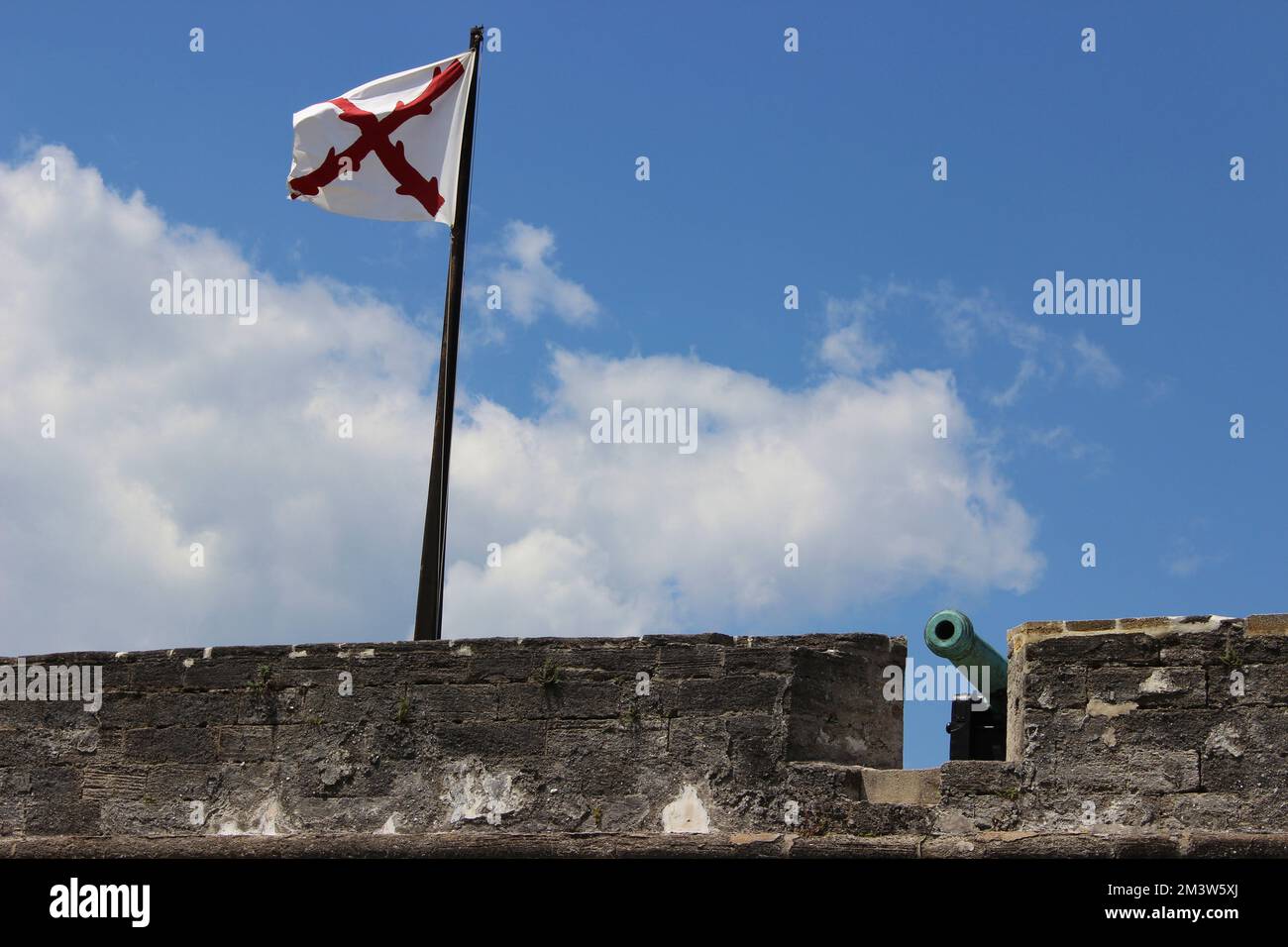 Parapet of an old stone fort flying the Cross of Burgundy with a cannon ...