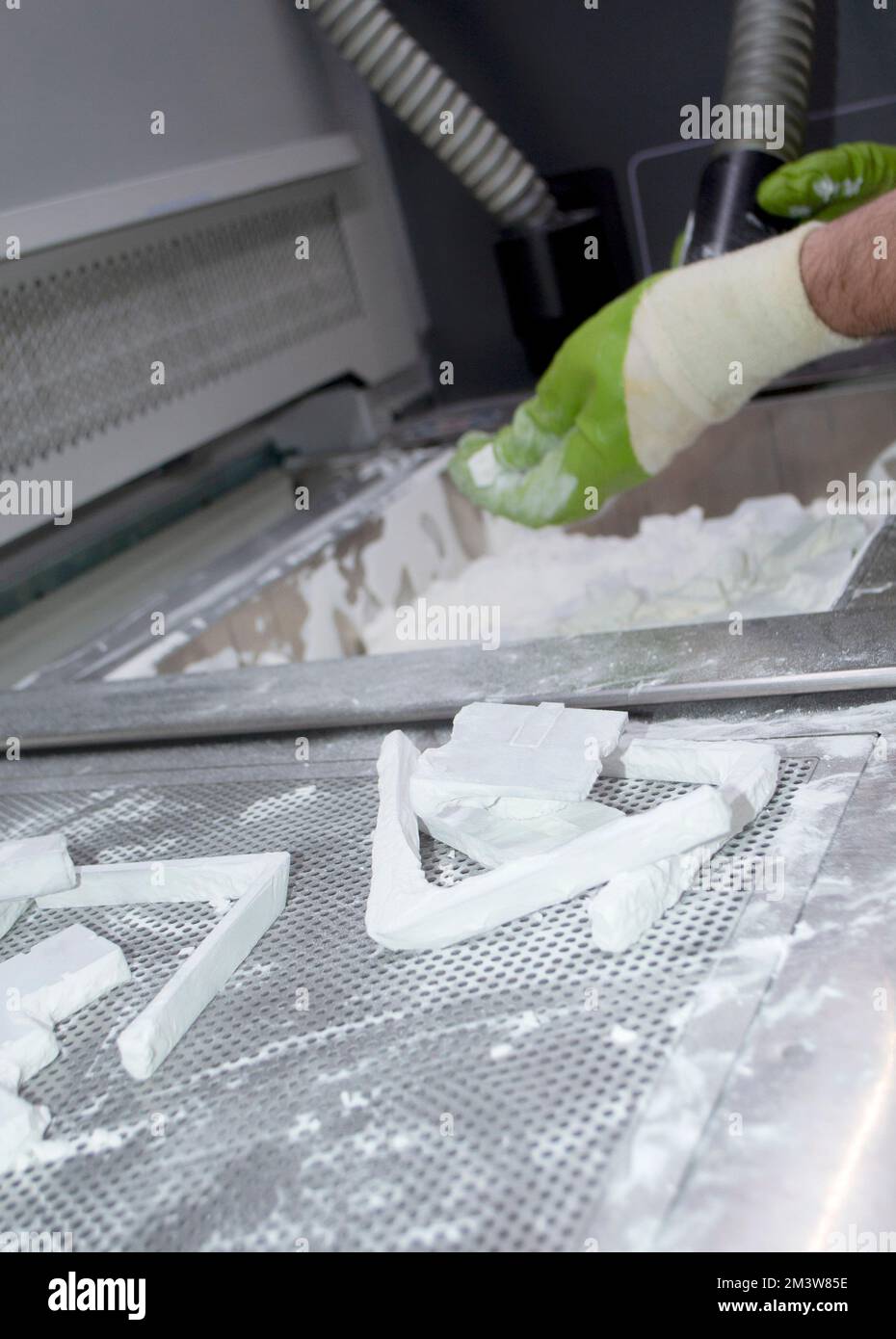 Male worker taking out models from white polyamide powder in working ...