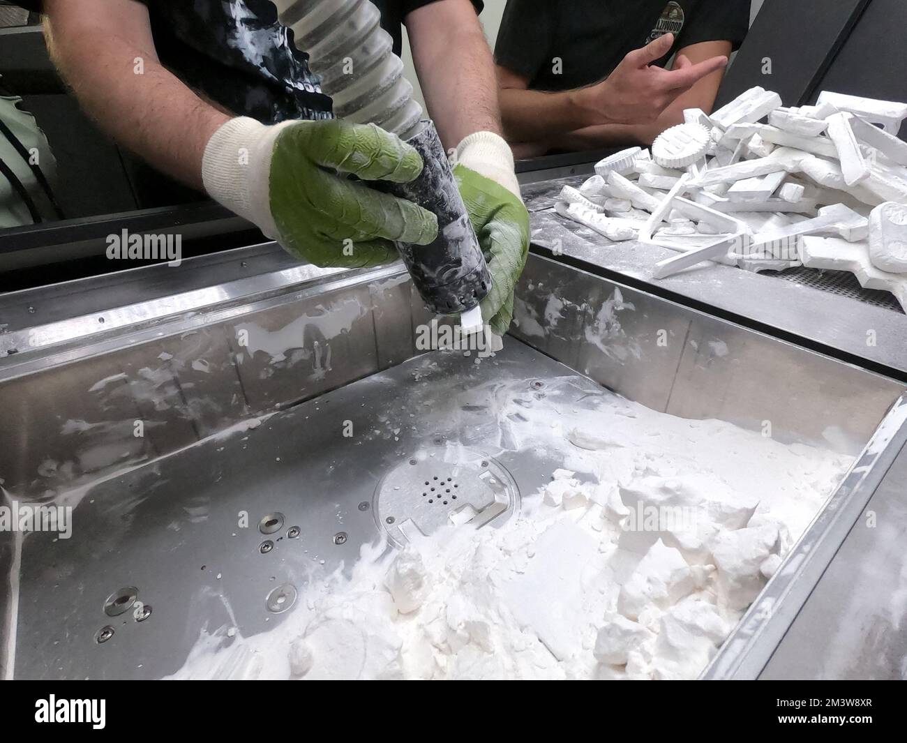 Male worker taking out models from white polyamide powder in working ...