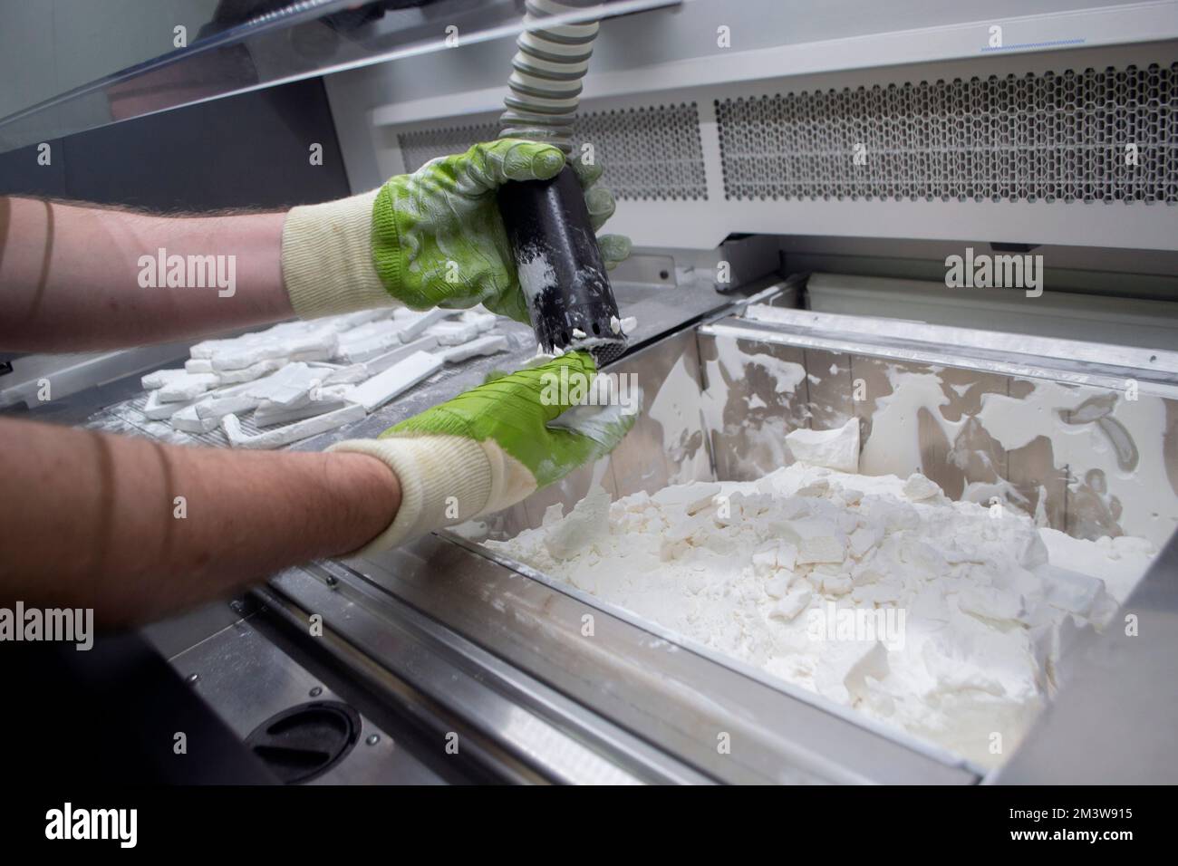 Male worker taking out models from white polyamide powder in working ...