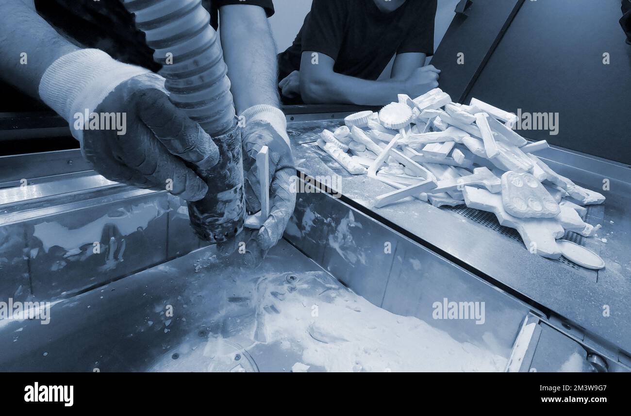 Mane taking out models from white polyamide powder in working chamber ...