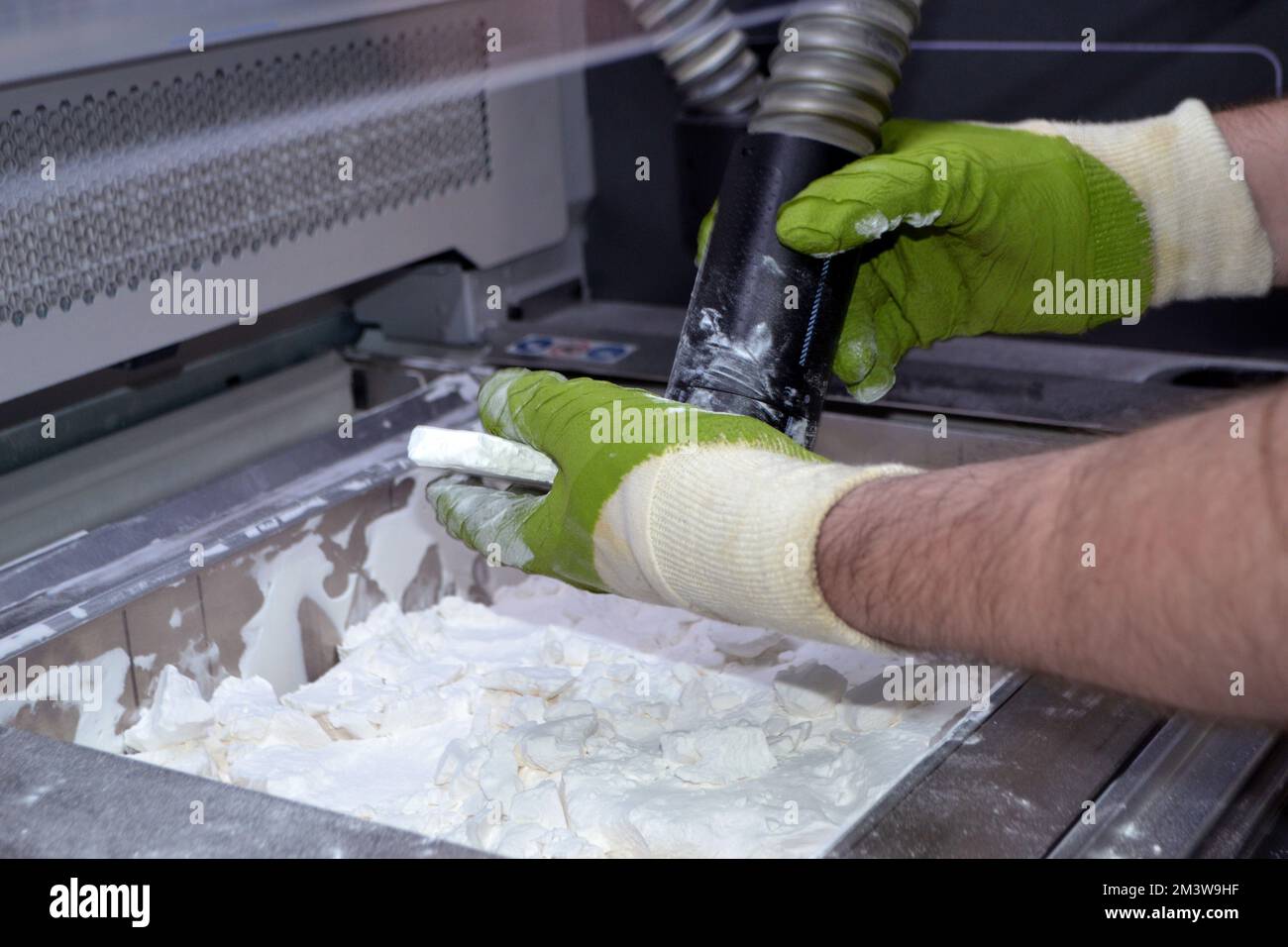 Mane taking out models from white polyamide powder in working chamber ...
