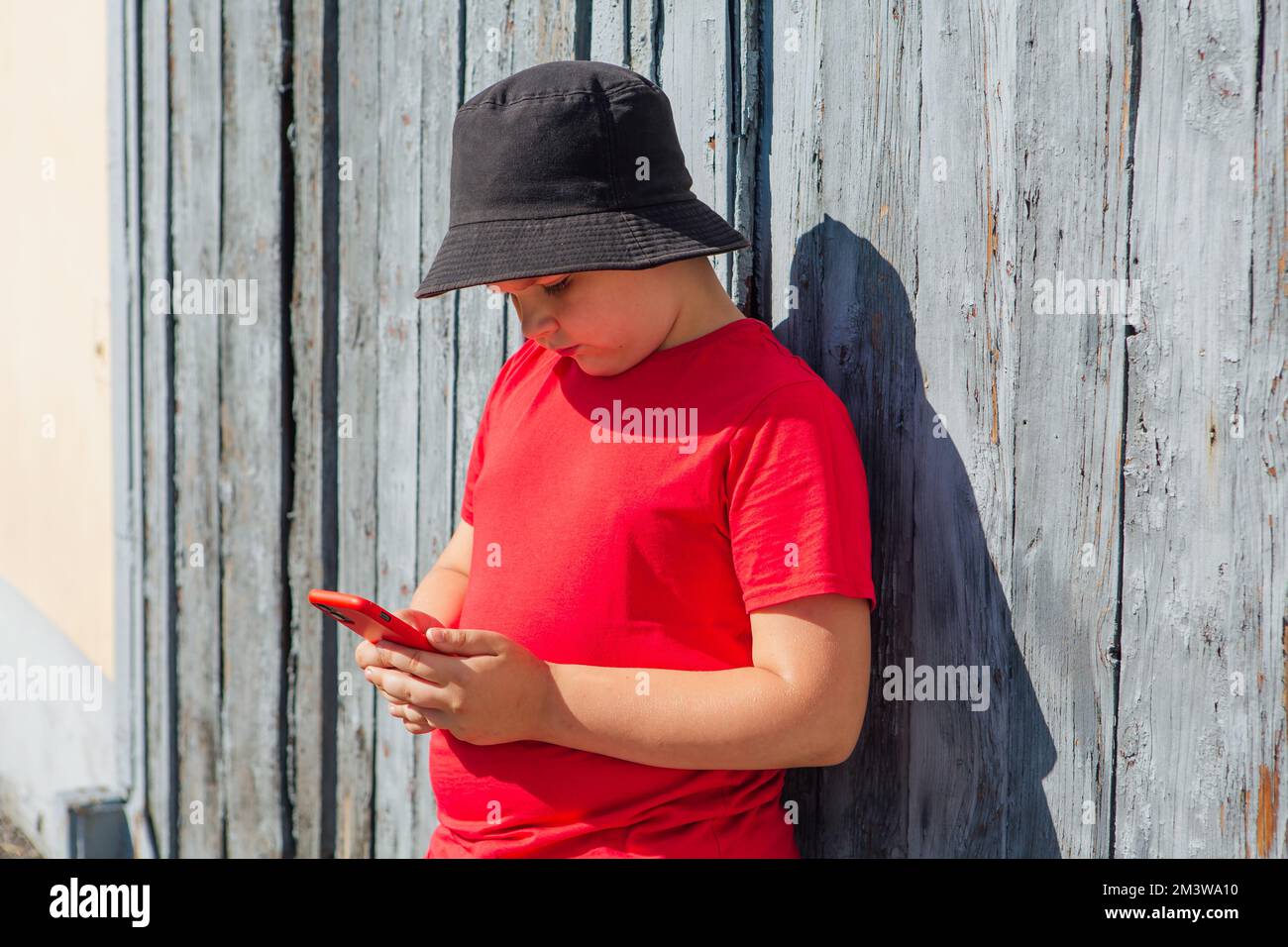 Happy chubby ten years old boy with staring at smartphone. Teen using ...
