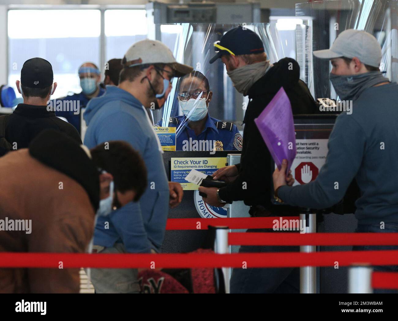 A TSA agent works behind a splatter guard at the security check area ...