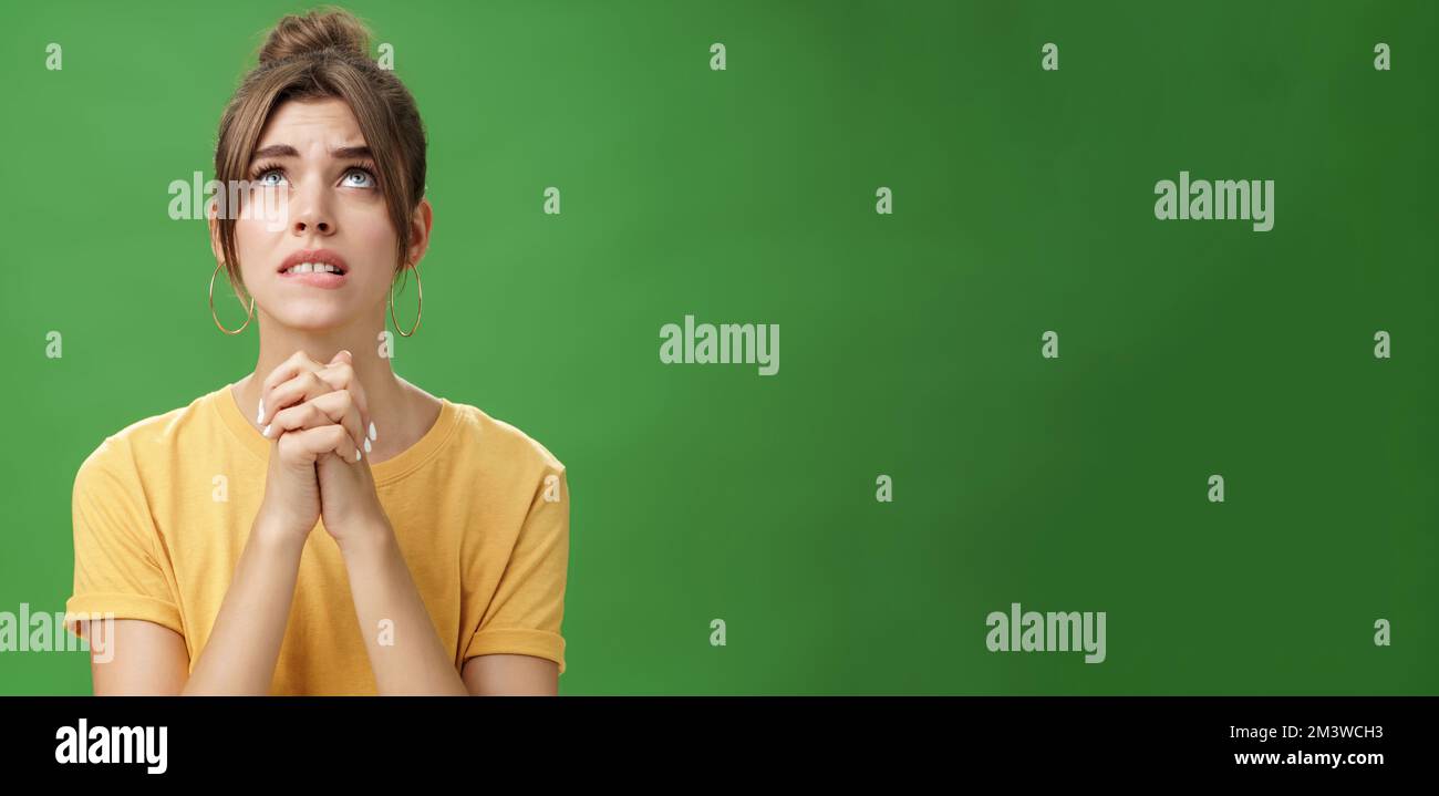 Intense nervous and faithful good-looking young woman clenching hands ...