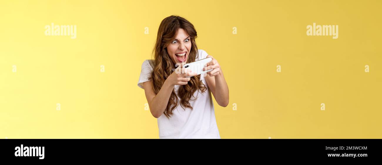 Excited intense playful gamer girl geek playing awesome smartphone game ...