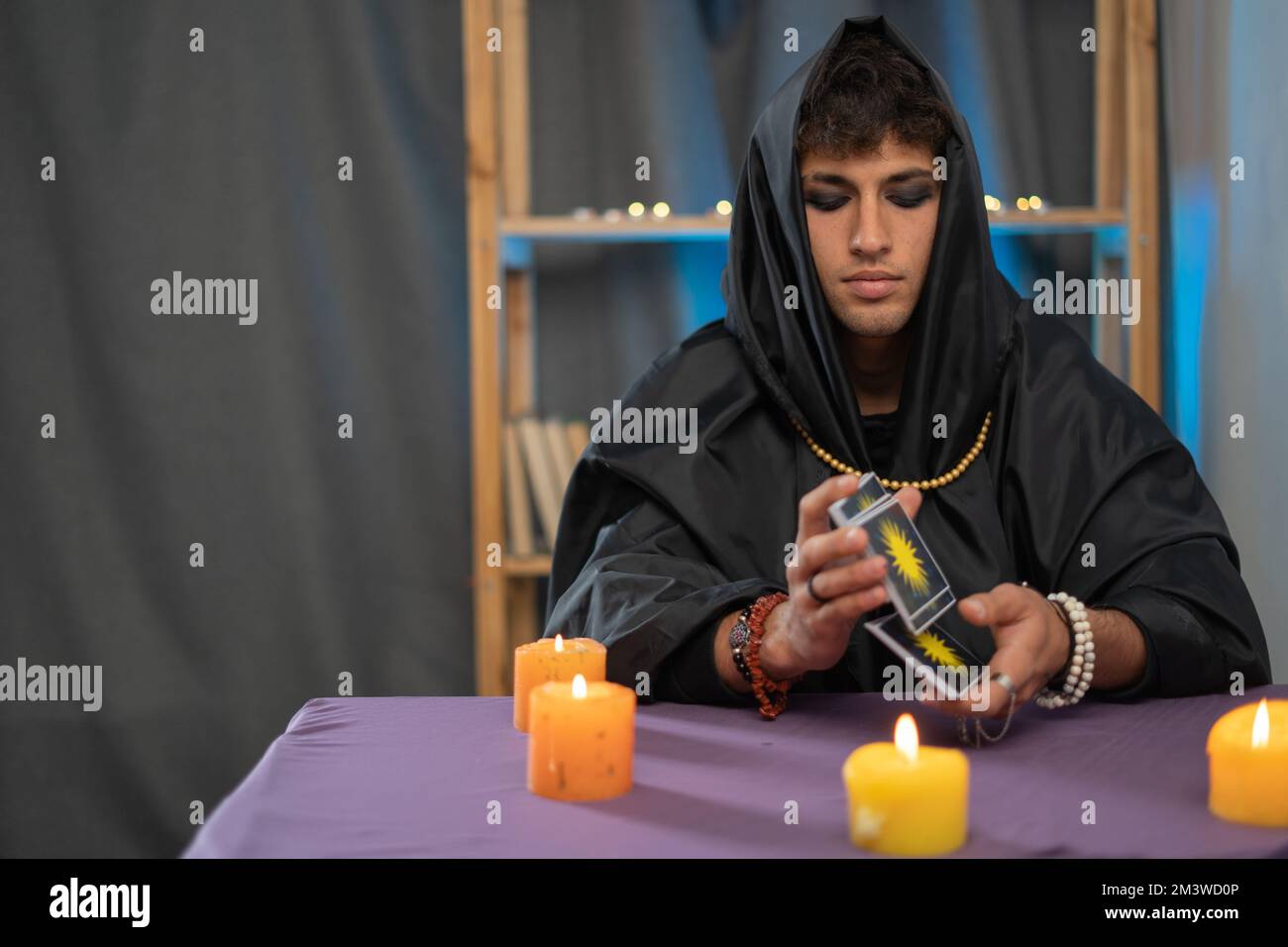 Pythoness man reads tarot cards on a table with candles. Copy space ...