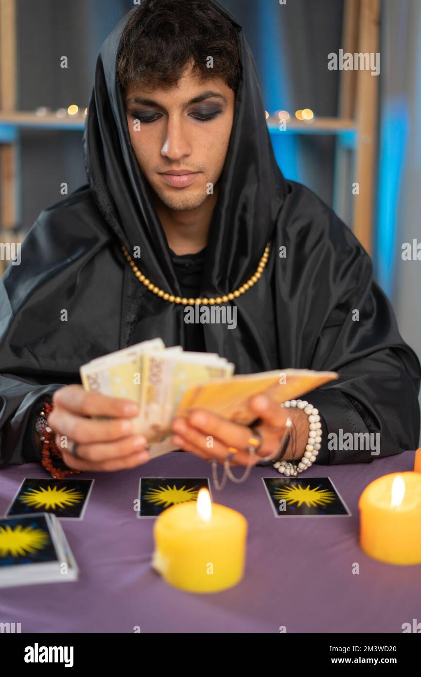 Male Fortune teller reading a future by tarot cards in the light of ...