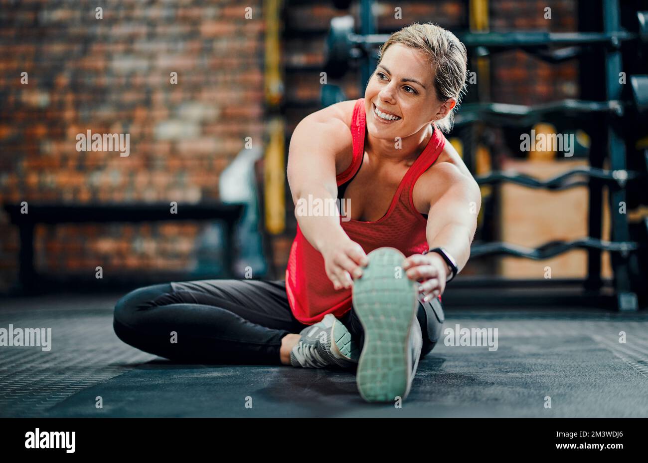 Stretch first, warmup second. Full length shot of an attractive young female athlete stretching ...