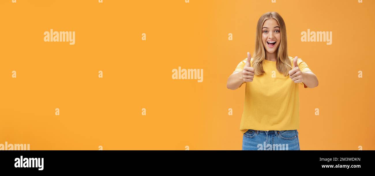 Woman supports with raised thumbs up and amused cheerful smile showing ...