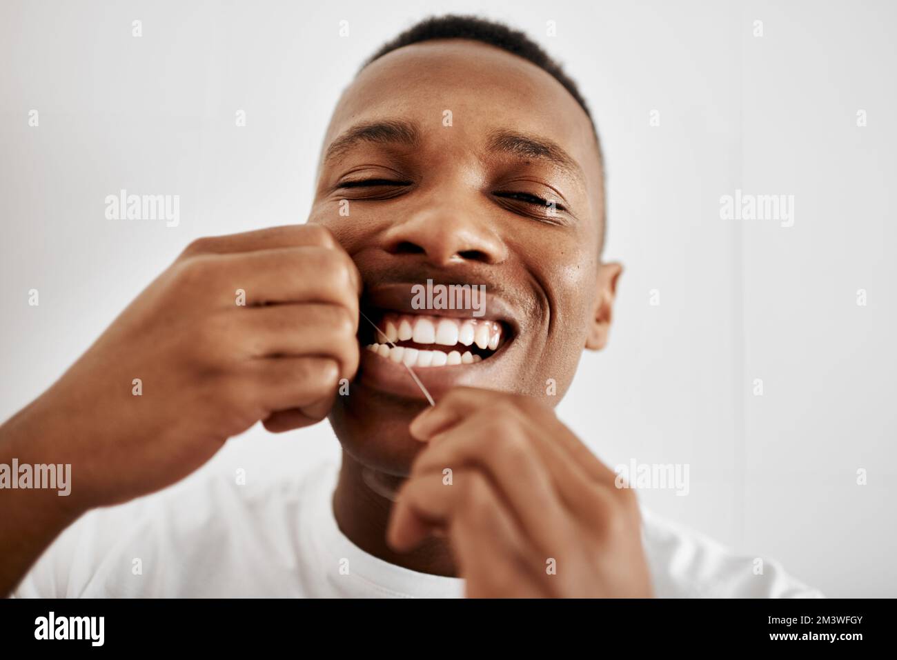 Flossing is just as important. a young man flossing his teeth in the bathroom at home Stock ...