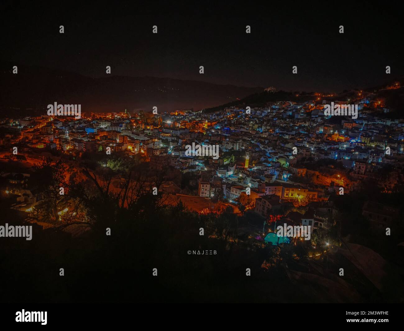 An aerial view of the Chefchaouen city illuminated with colorful lights ...