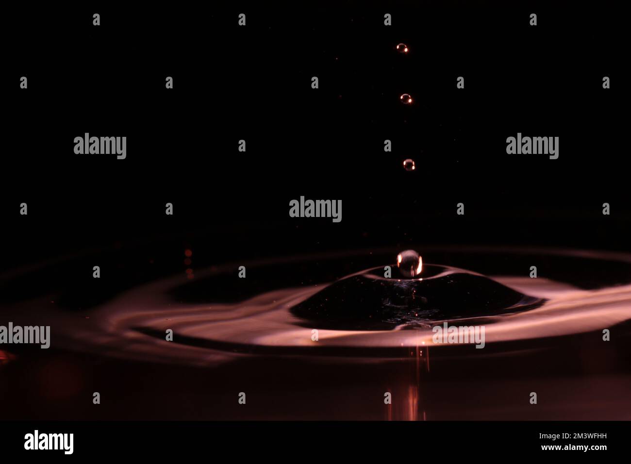 The water drops splashing into the dark surface of water Stock Photo ...