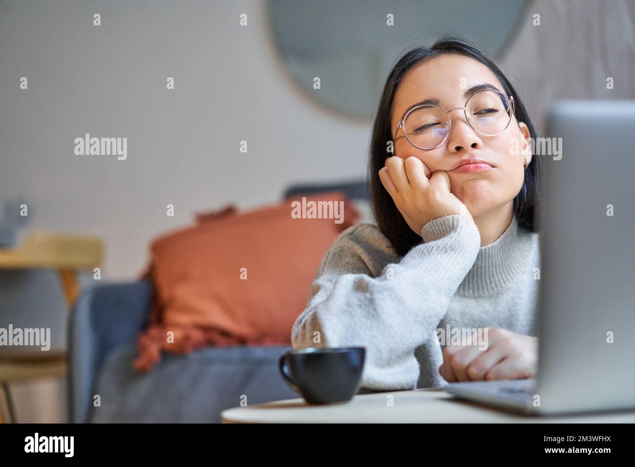 Portrait of korean girl sits bored, student looks gloomy at laptop, sitting at home and ...