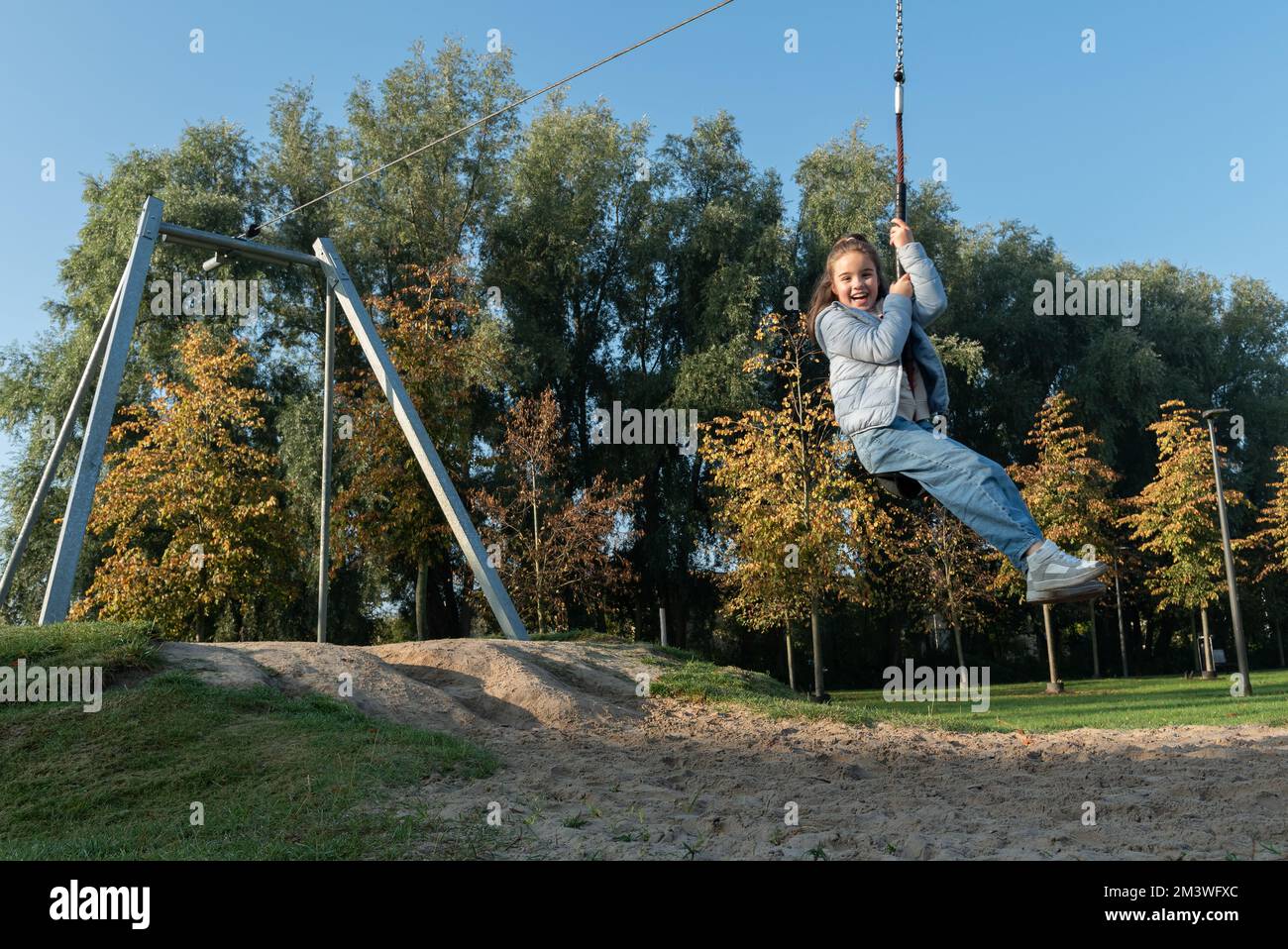 Autumn recreation in nature. Young girl riding a hanging bungee on the ...