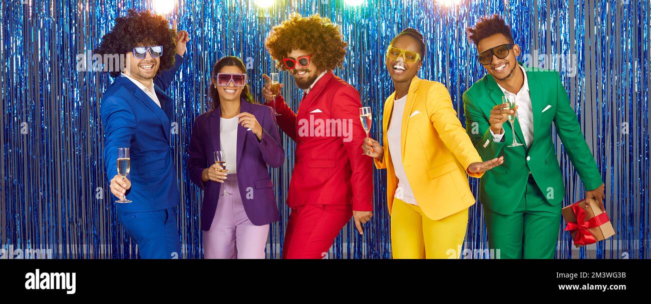 Happy friends or colleagues dancing with glasses of champagne at themed ...