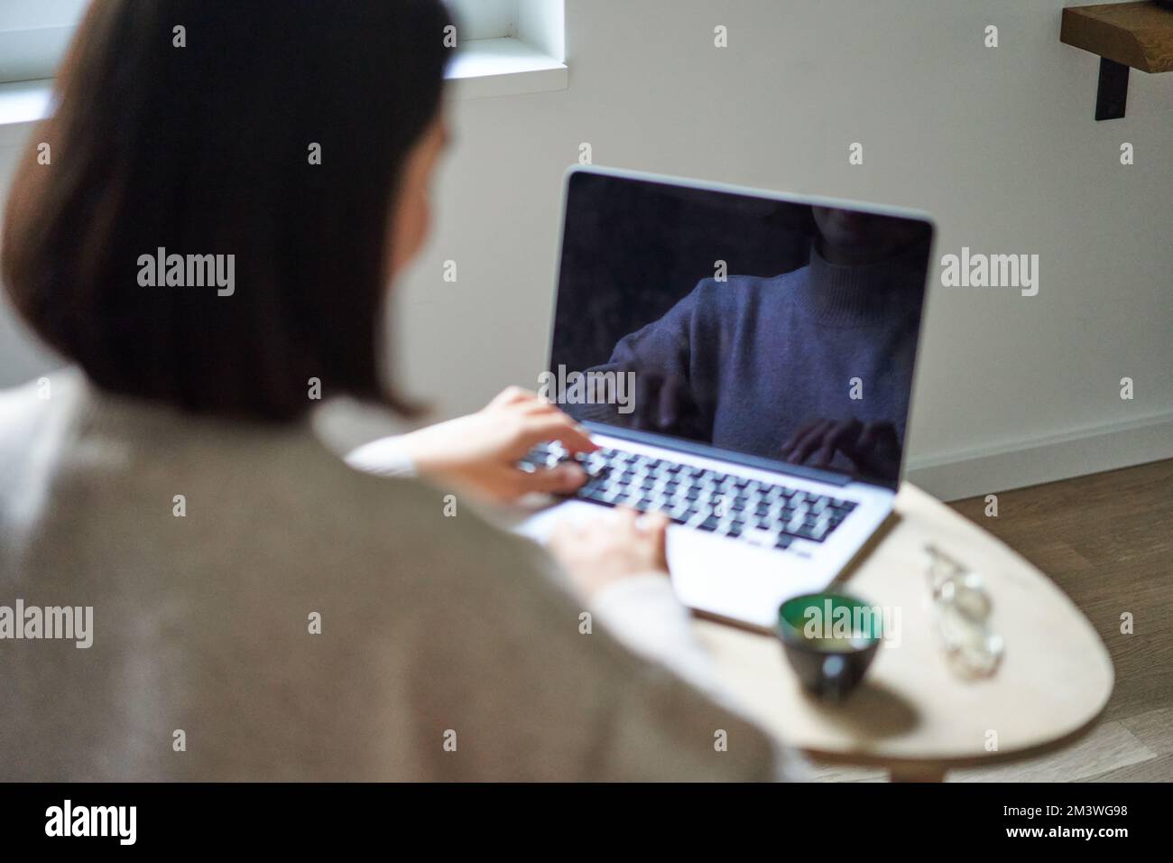 Rear view of woman, typing and working on laptop, computer screen is ...