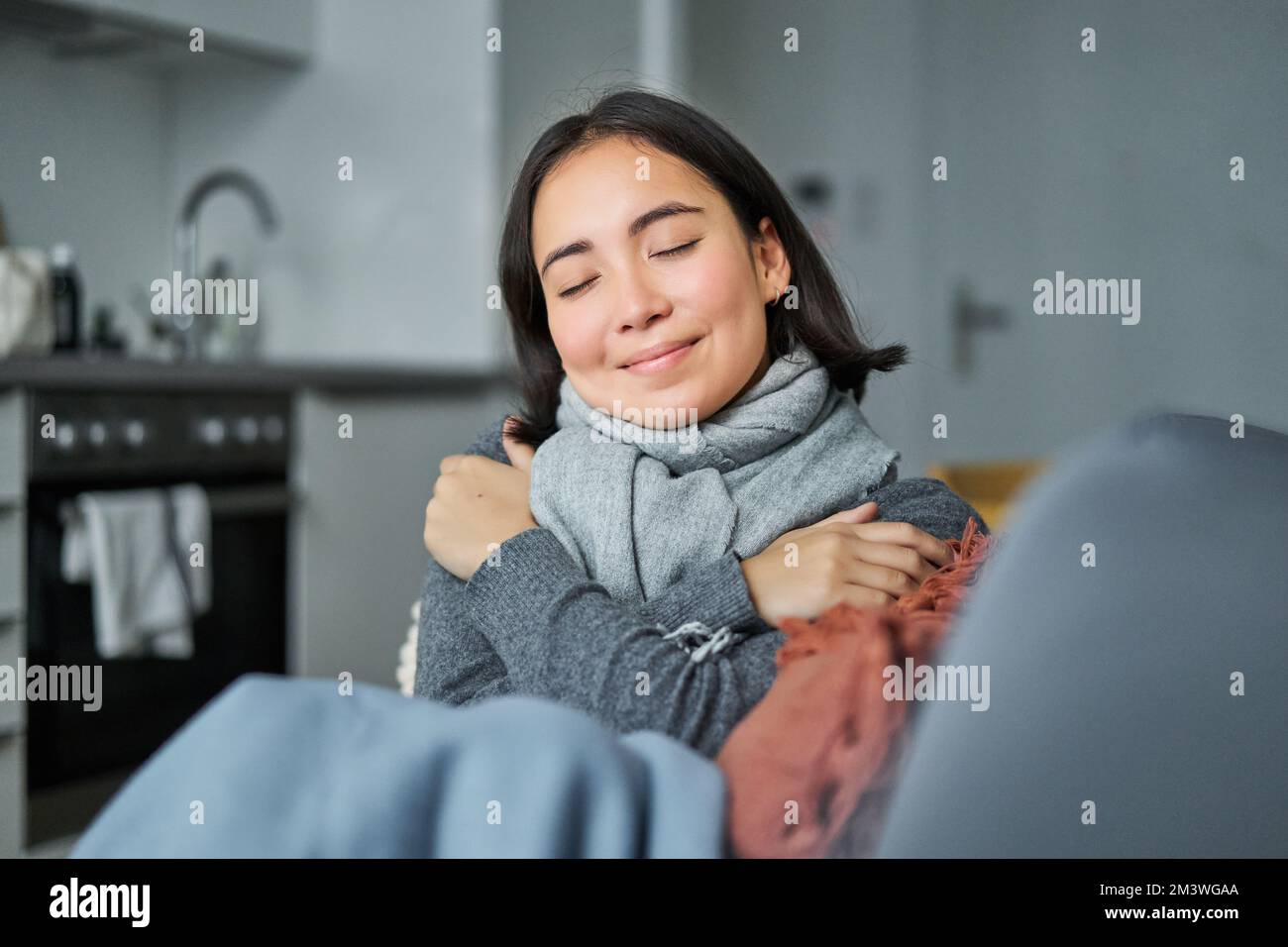 Portrait of smiling asian woman feels warmth, hugs herself with pleased ...