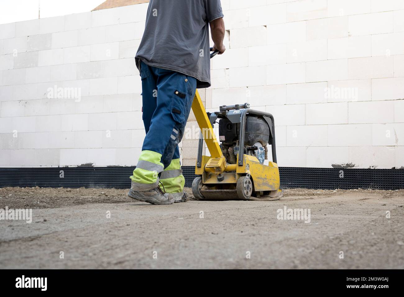 A view from behind of a worker using a compaction machinery Stock Photo ...