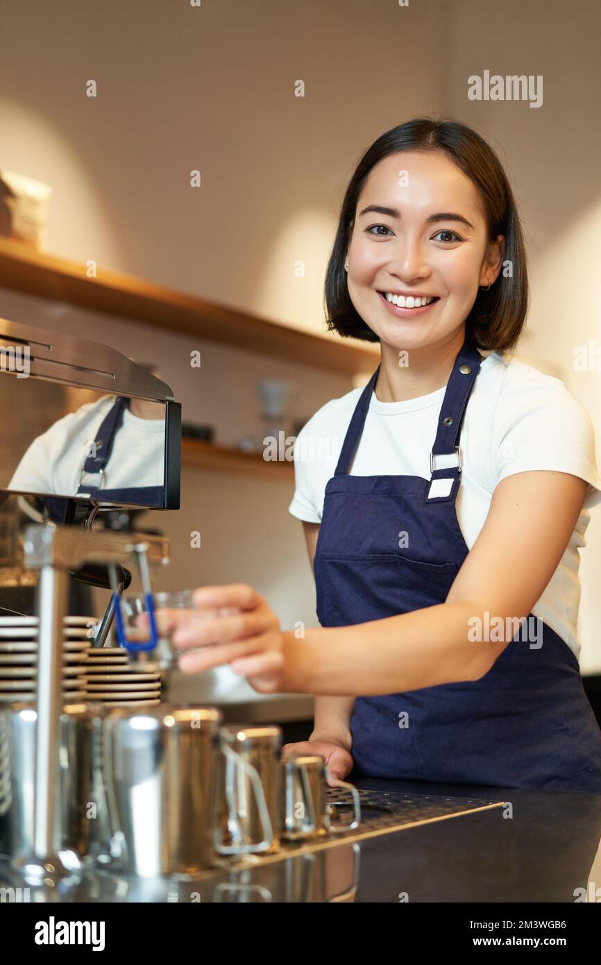 Vertical shot of young professional, smiling girl barista working in ...